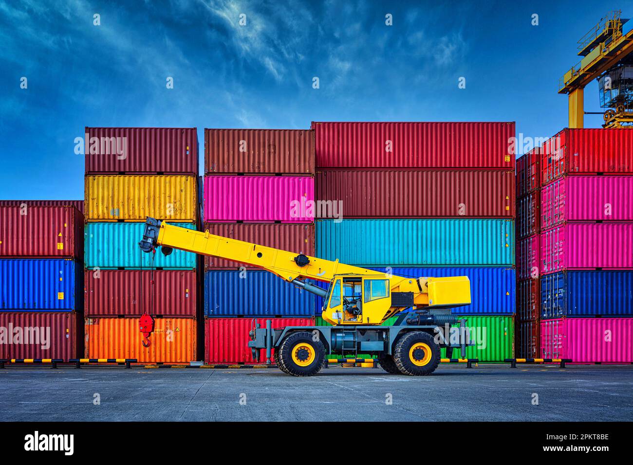 A cargo crane is in the process of transferring large colorful shipping ...