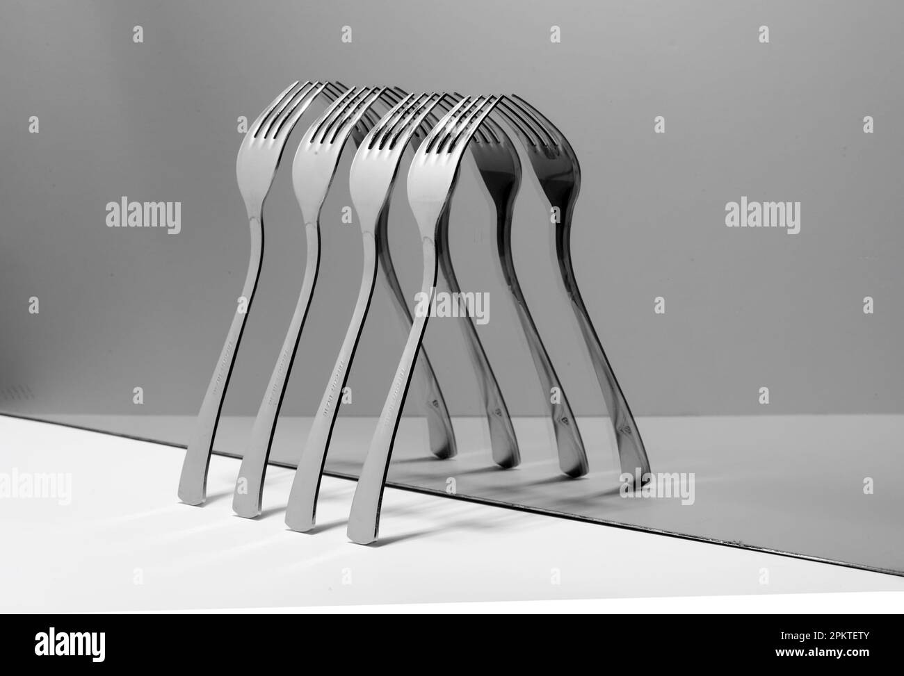 stainless steel forks and symmetrically mirror reflection on a white ...