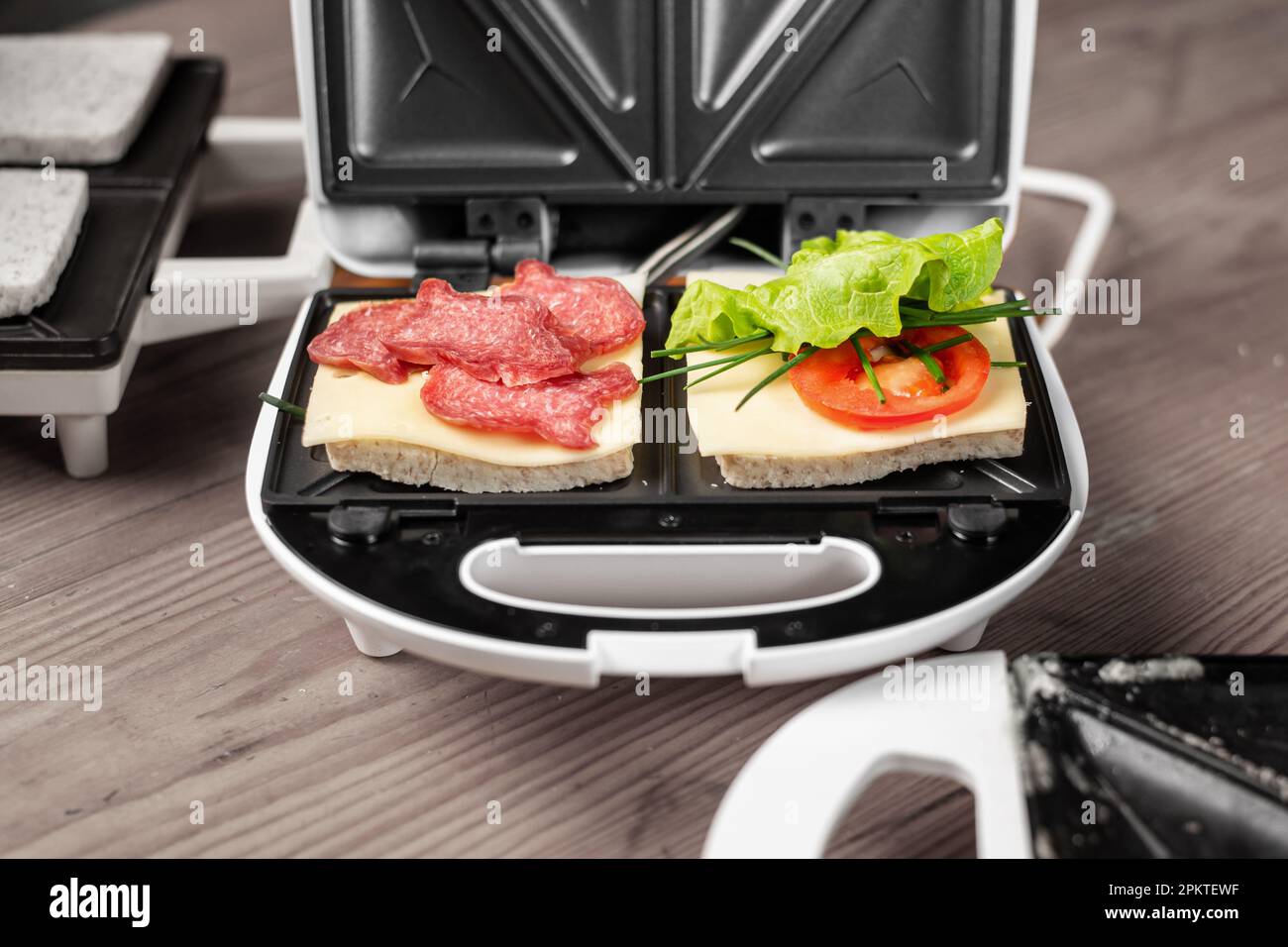 A sandwich maker with two different sandwiches with tomatoes, ham ...