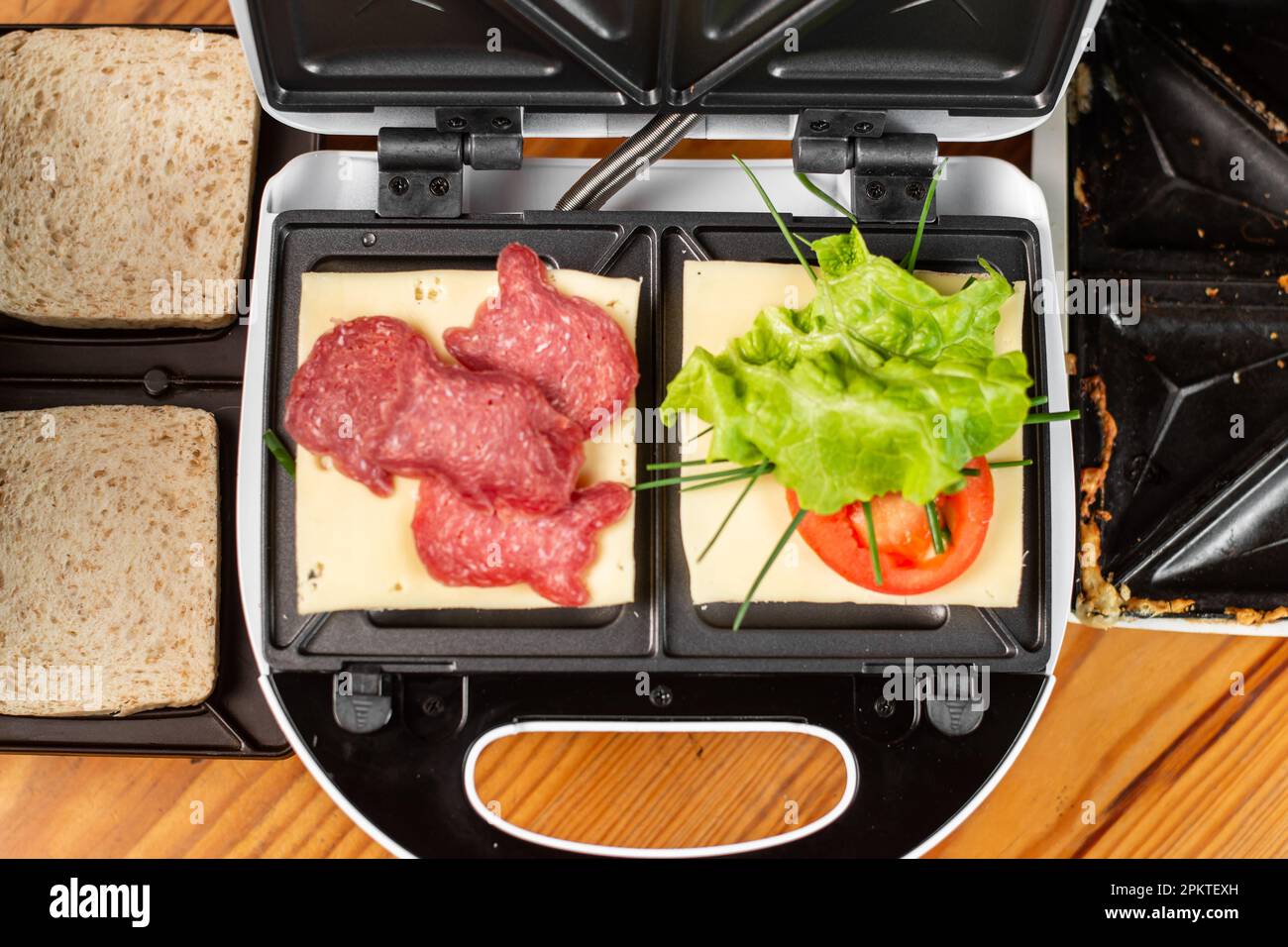 A sandwich maker with two different sandwiches with tomatoes, ham ...