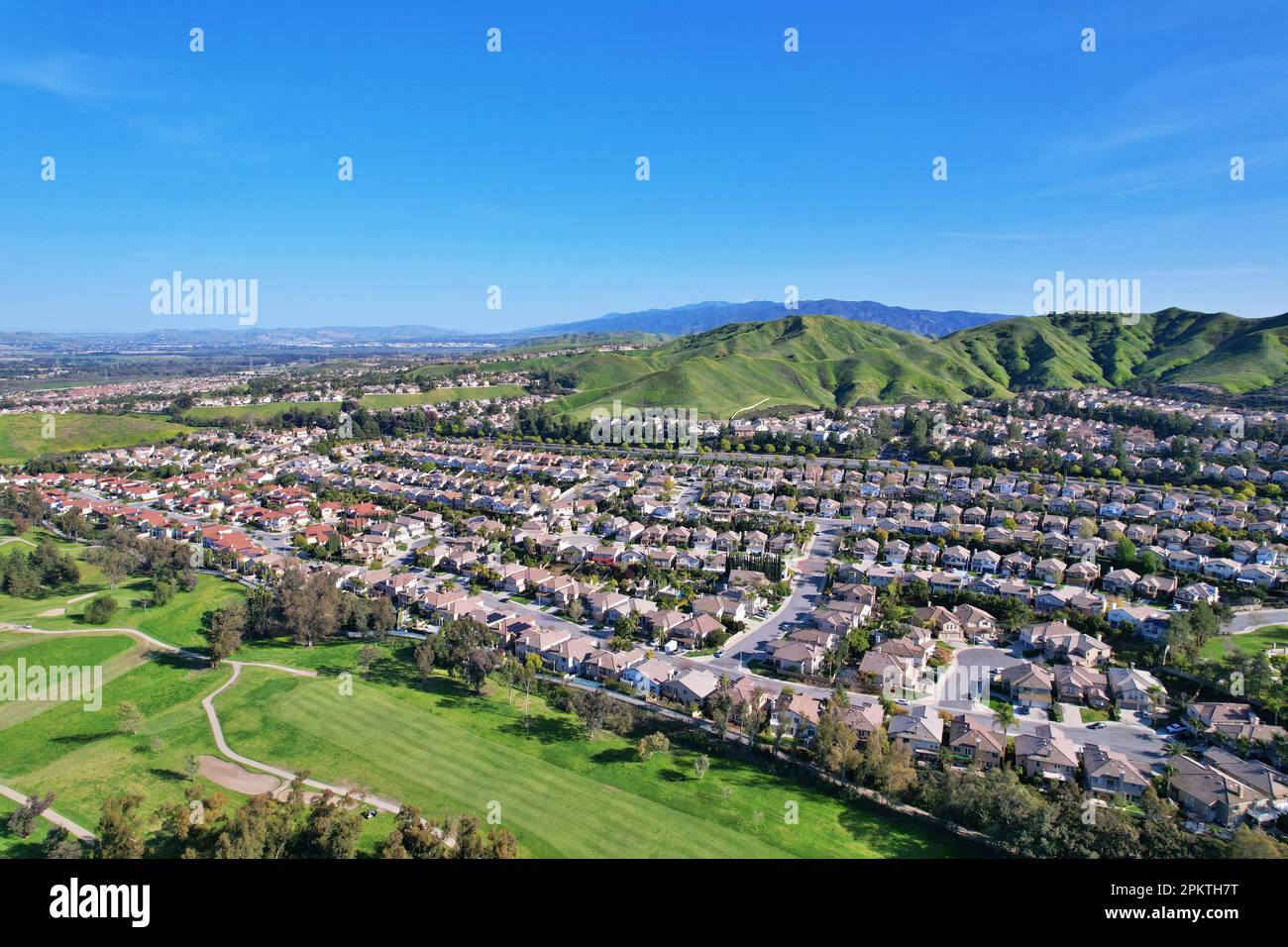 Aerial view of lush green grass and trees, with a backdrop of mountains ...