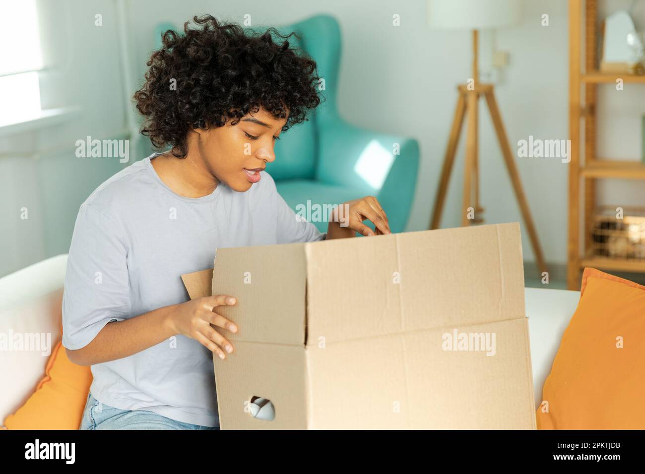 African girl unpacking delivery looking in box. Happy woman opening ...