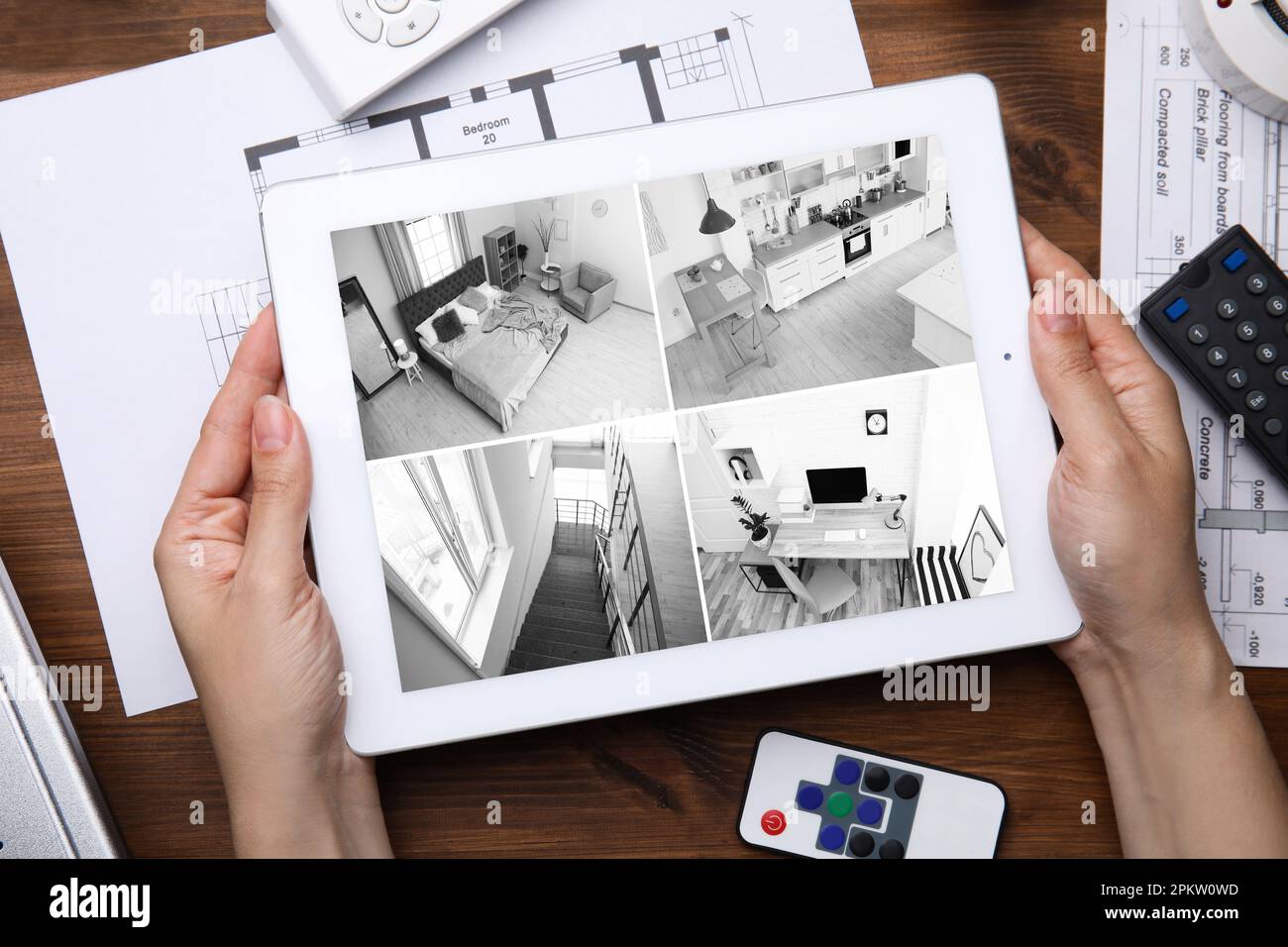 Woman monitoring CCTV cameras on tablet at wooden table, top view. Home ...