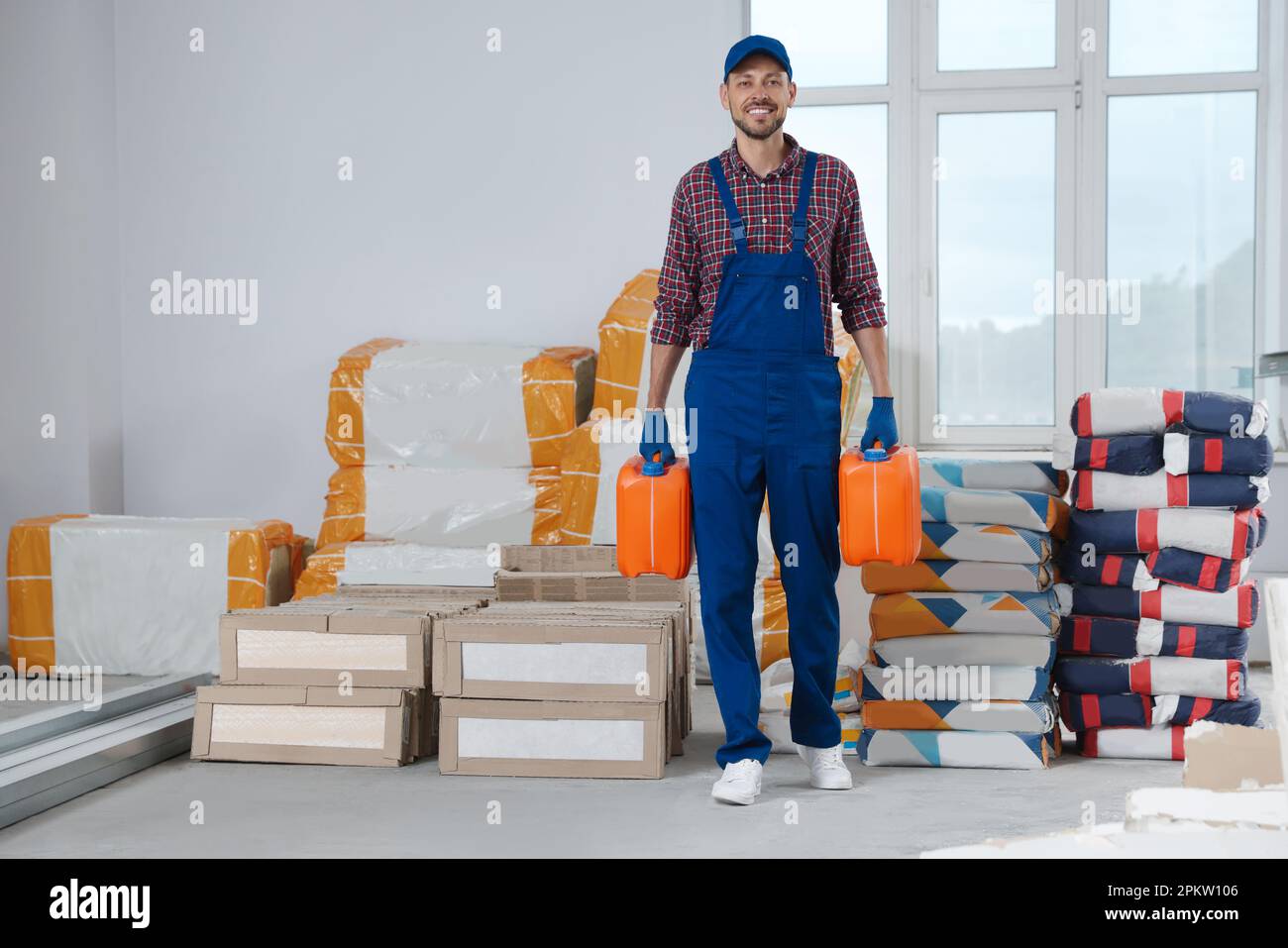 Construction worker carrying canisters in room prepared for renovation ...