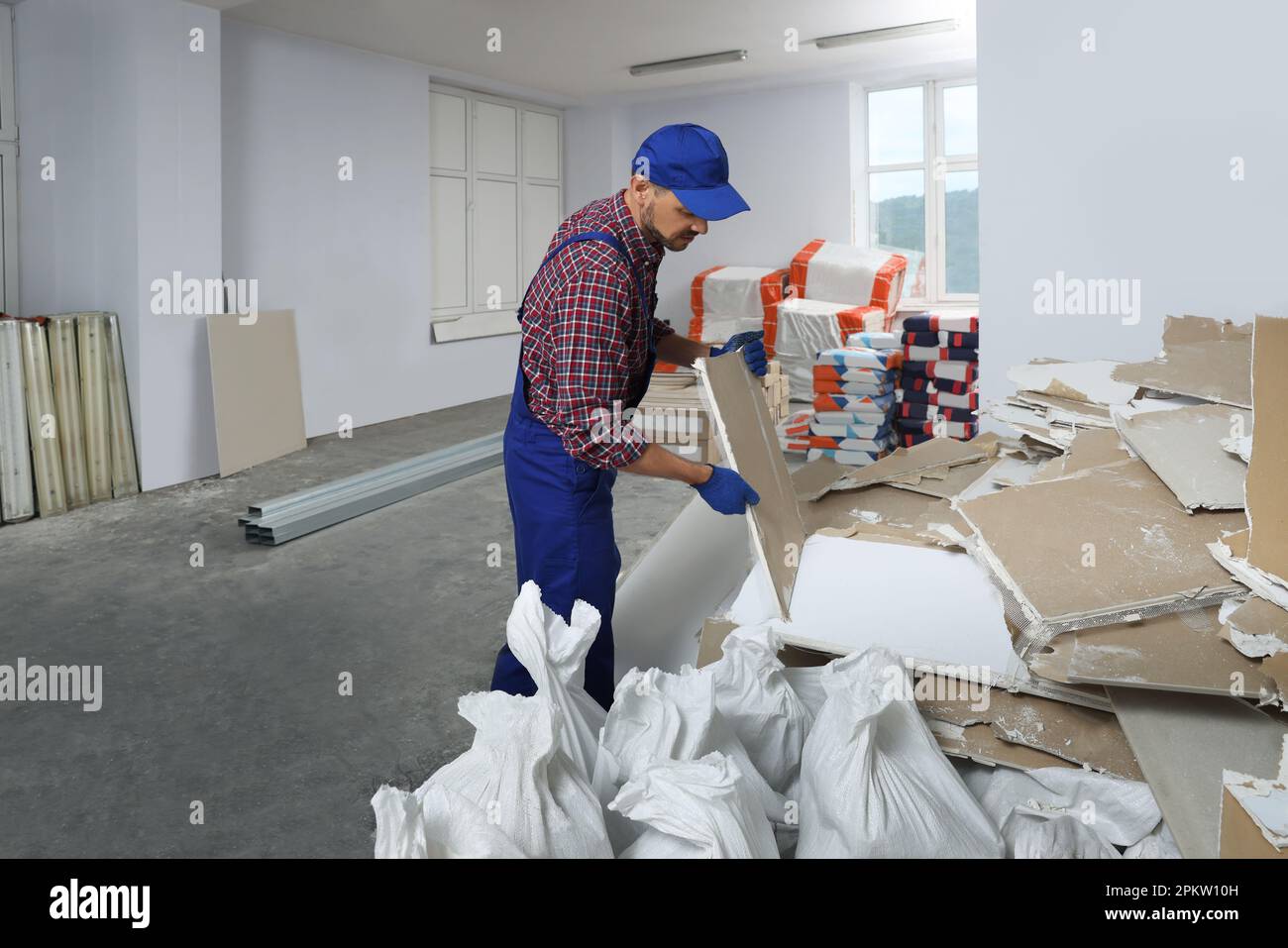 Construction worker carrying used drywall in room prepared for ...