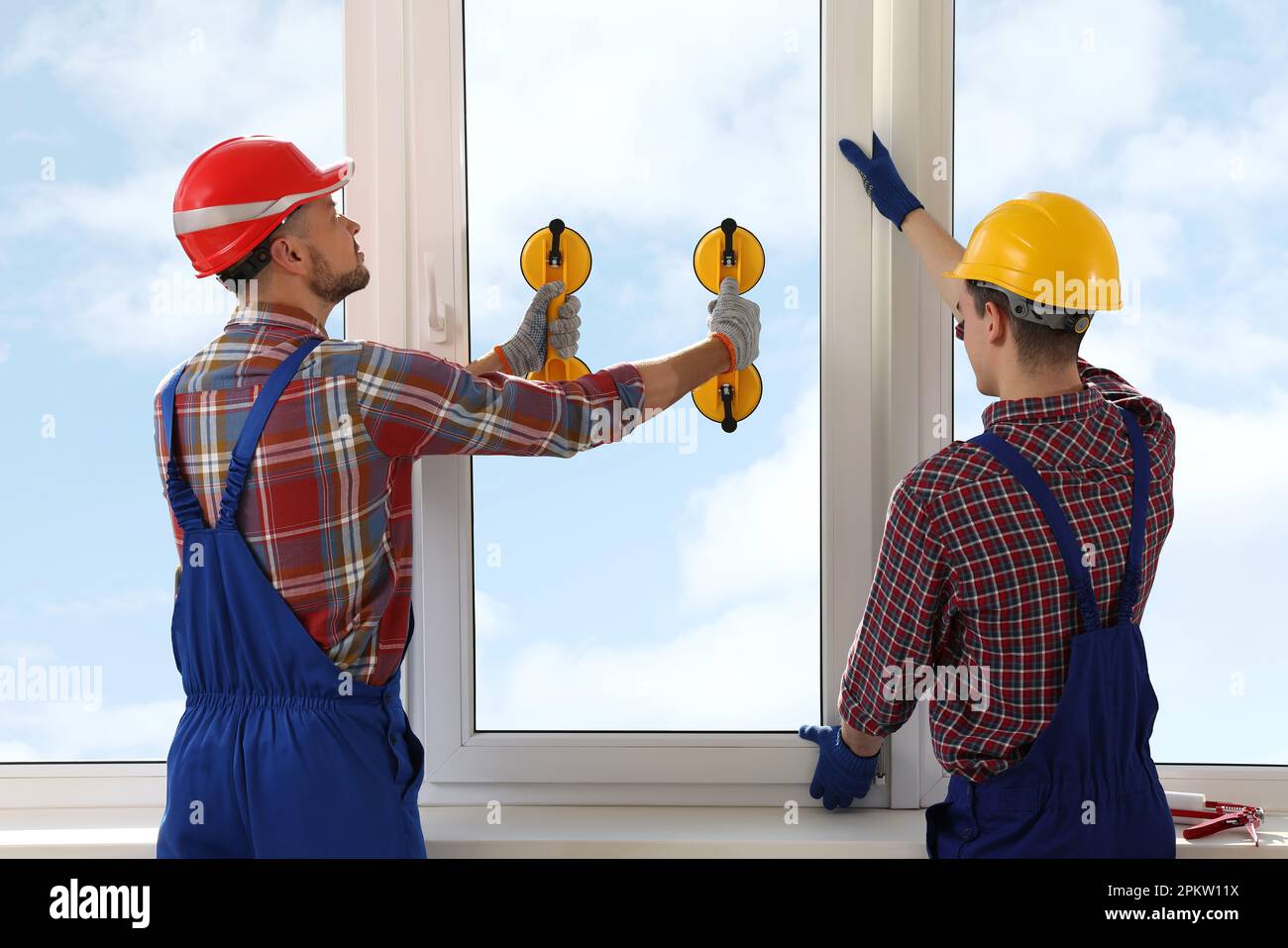 Workers using suction lifters during plastic window installation ...