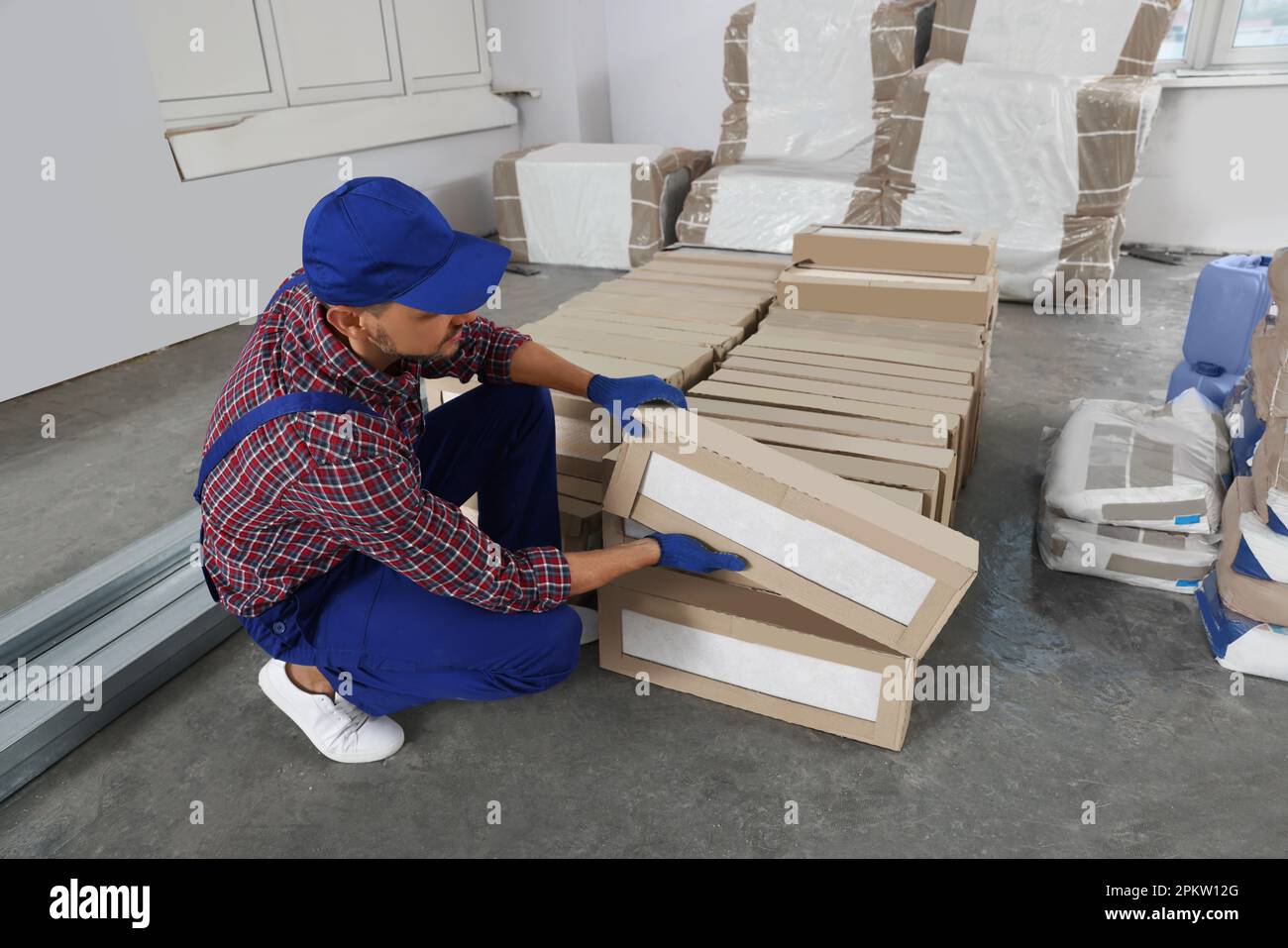 Construction worker with packed new boxes in room prepared for ...
