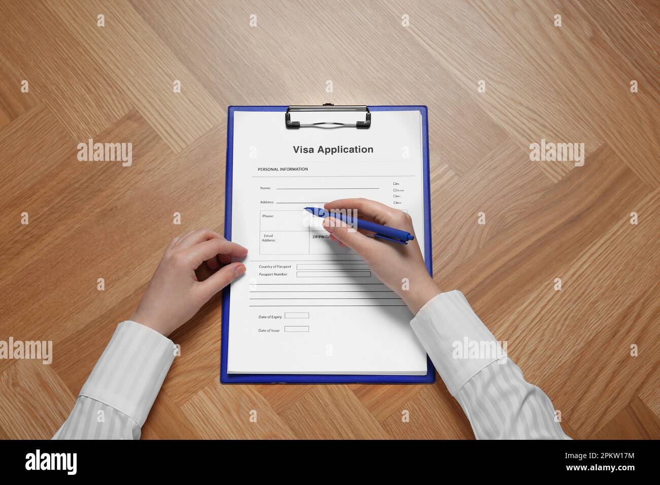 Woman filling visa application form for immigration at table, top view ...