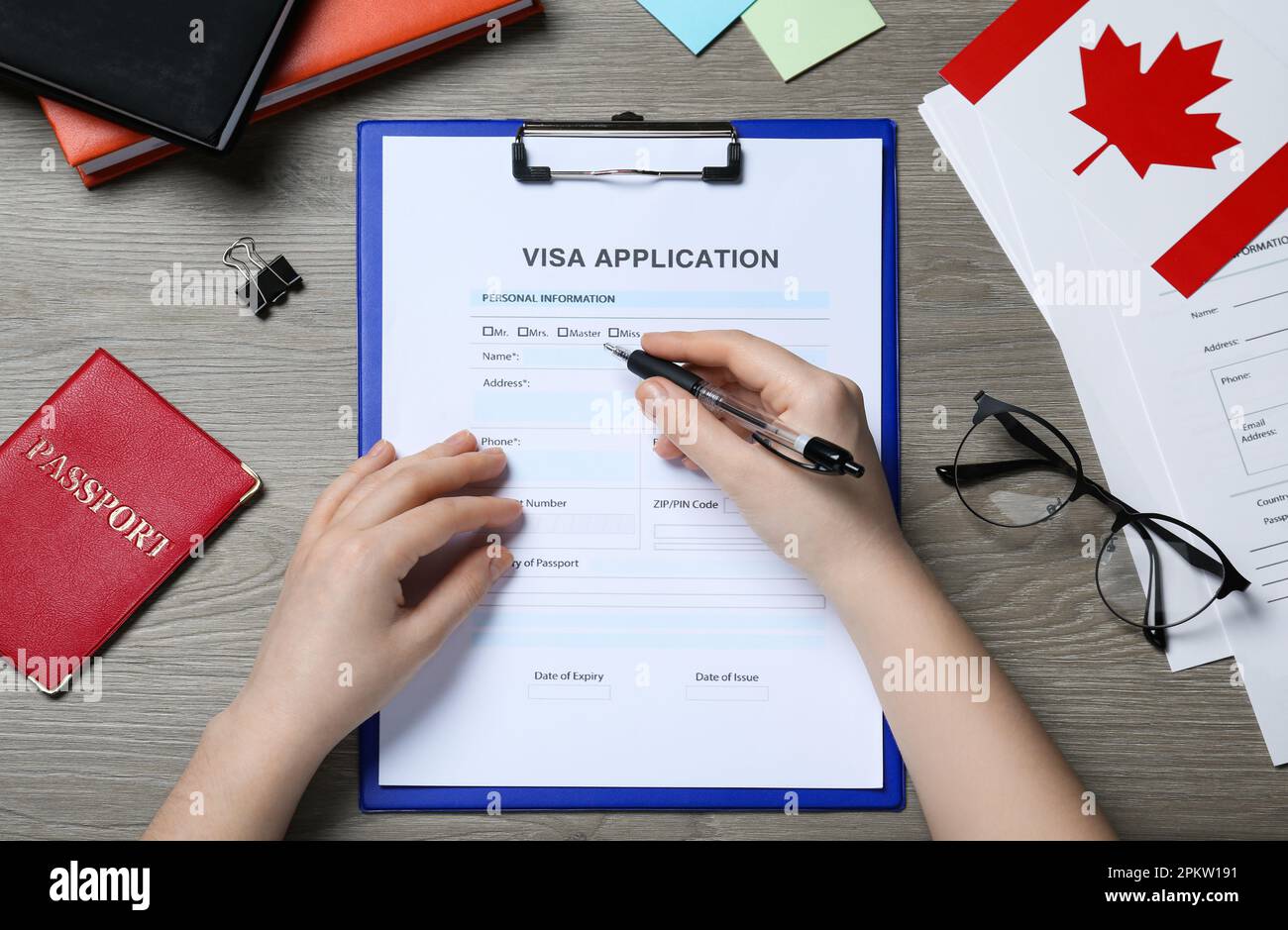 Woman filling visa application form to Canada at wooden table, top view ...