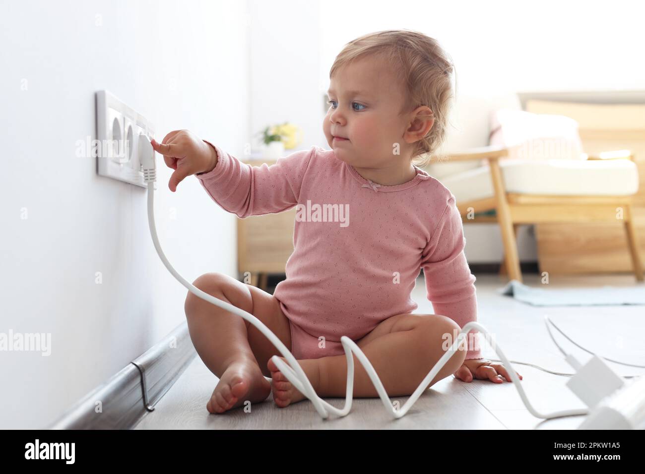 Cute baby playing with electrical socket and plug at home. Dangerous ...