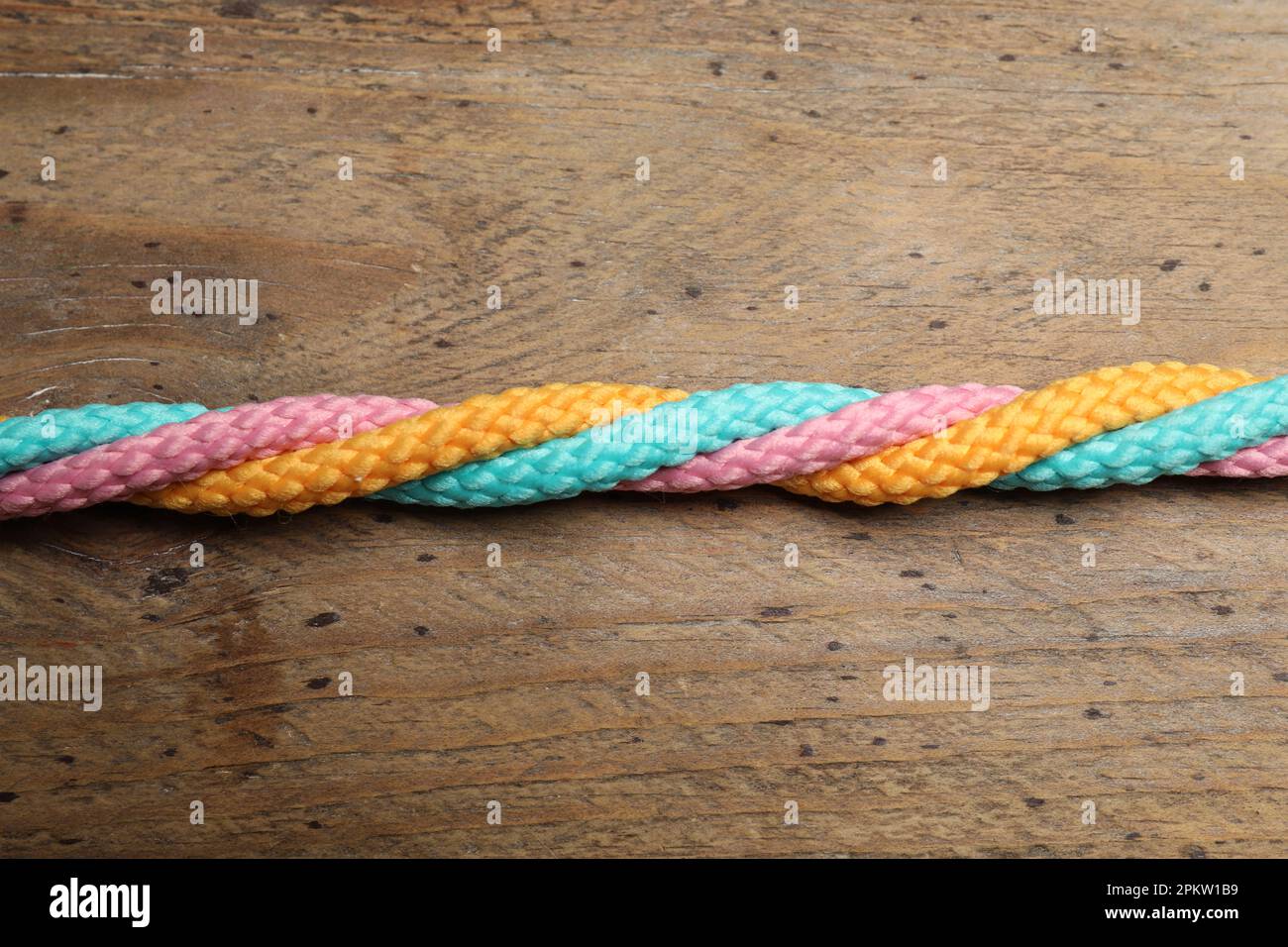 Twisted colorful ropes on wooden background, top view. Unity concept ...