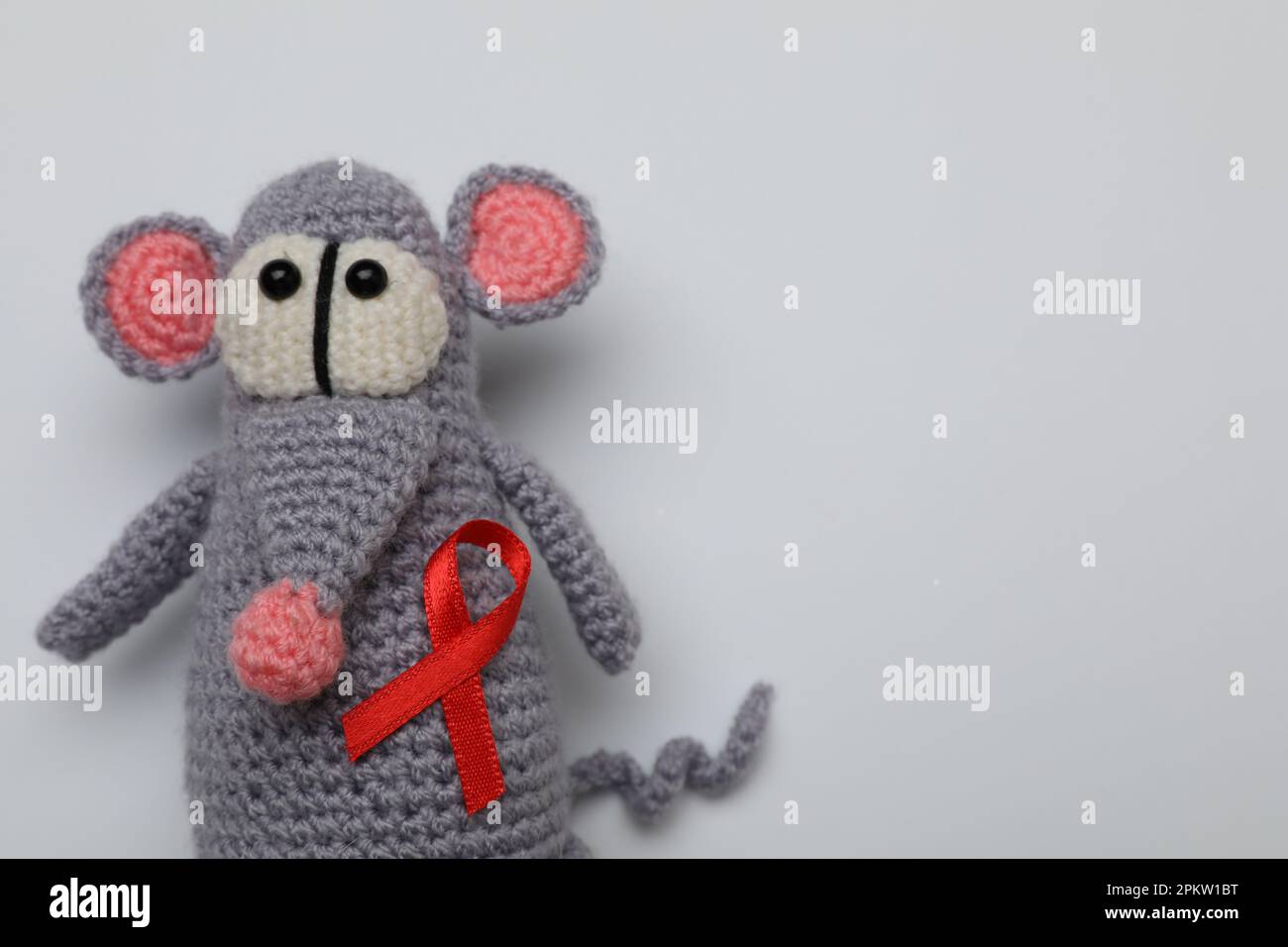 Cute knitted toy mouse with red ribbon on light grey background, top ...