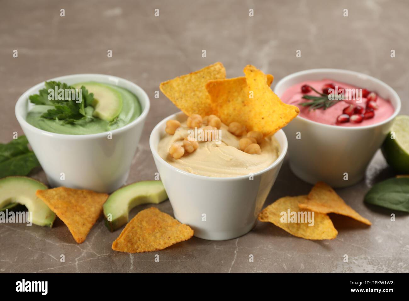 Composition with different delicious hummuses on brown marble table ...