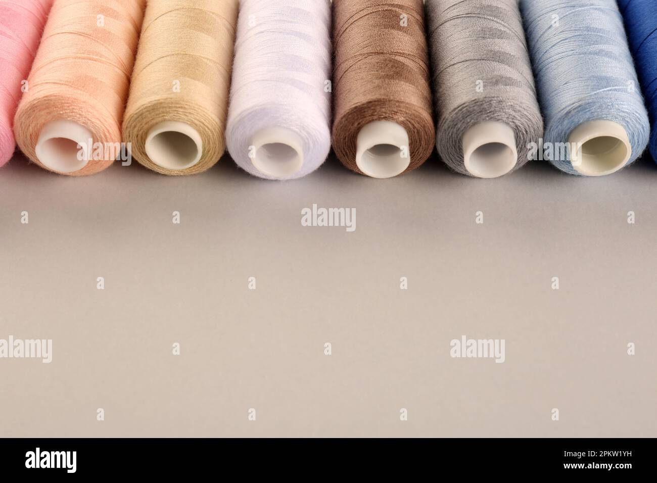 Different sewing threads on light grey background. Space for text Stock ...