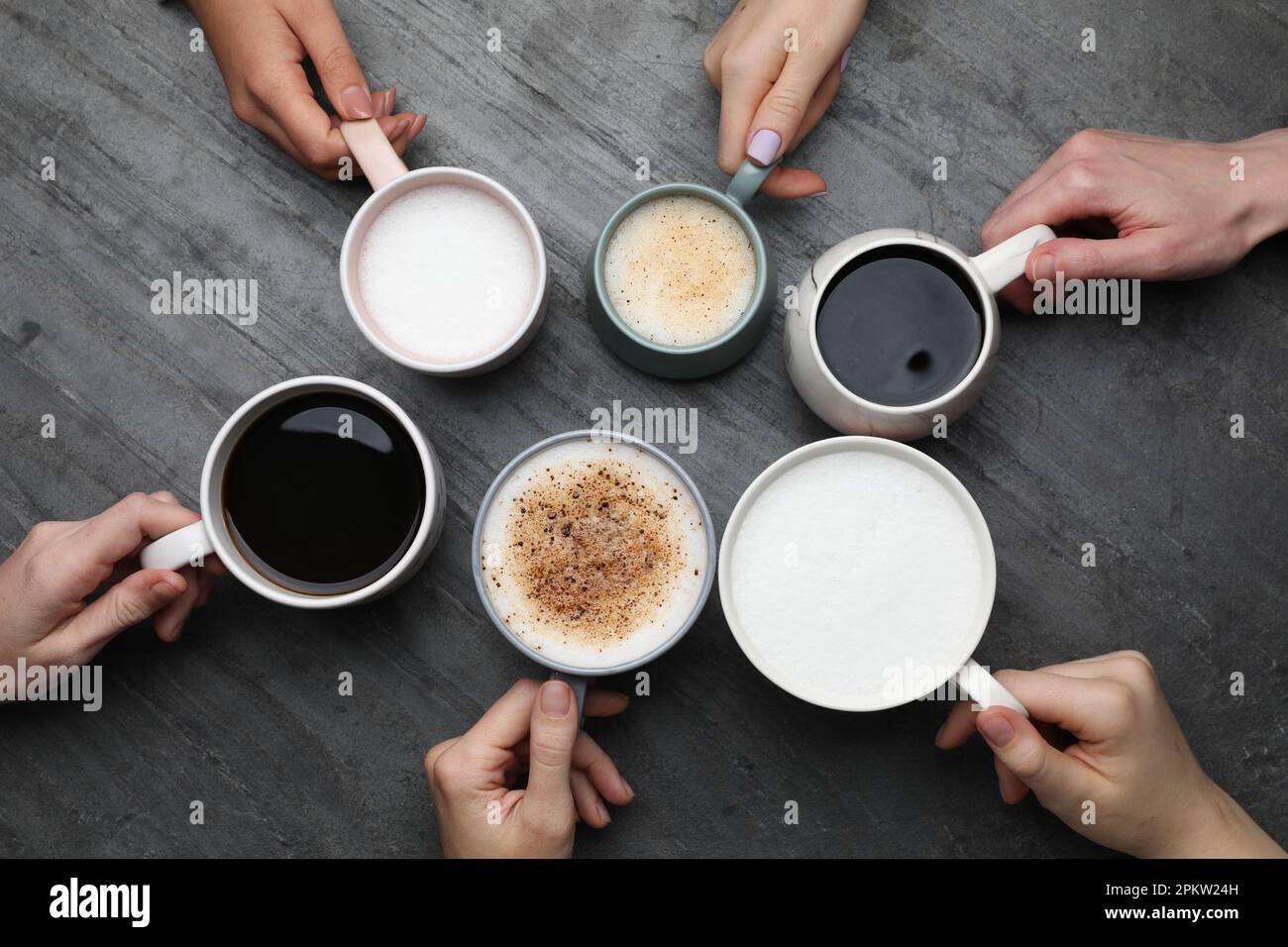 People holding different cups with aromatic hot coffee at grey table ...