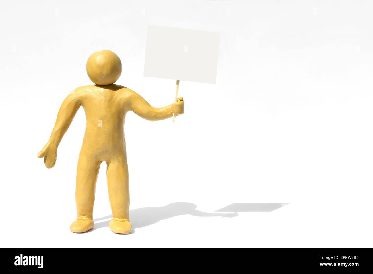 Human figure made of yellow plasticine holding blank sign on white ...