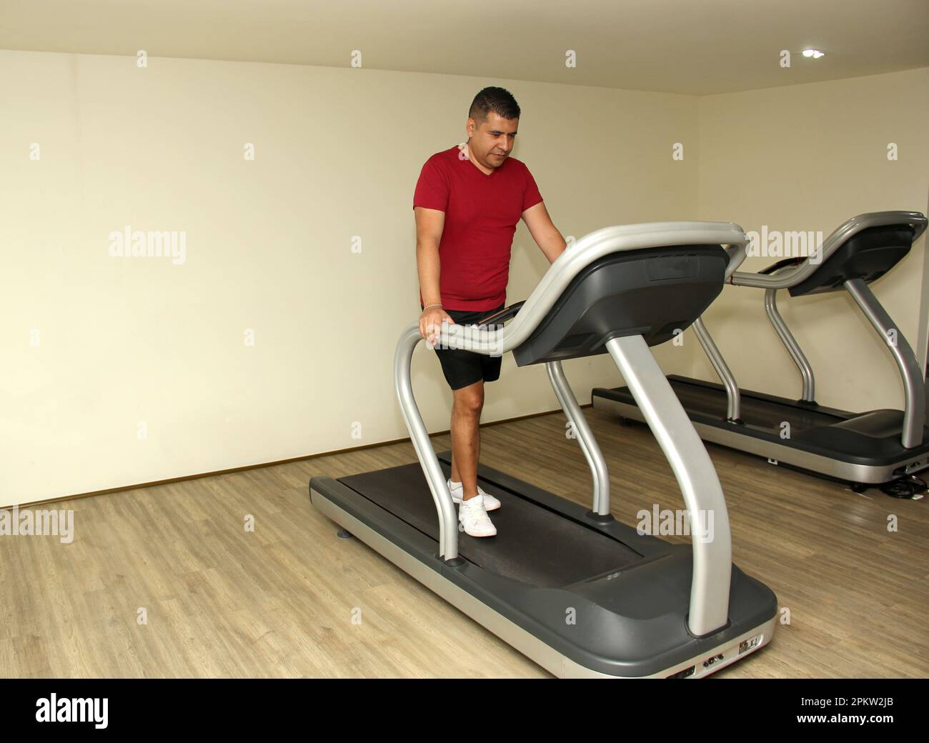 Overweight dark-haired latino adult man exercises on treadmill in gym ...