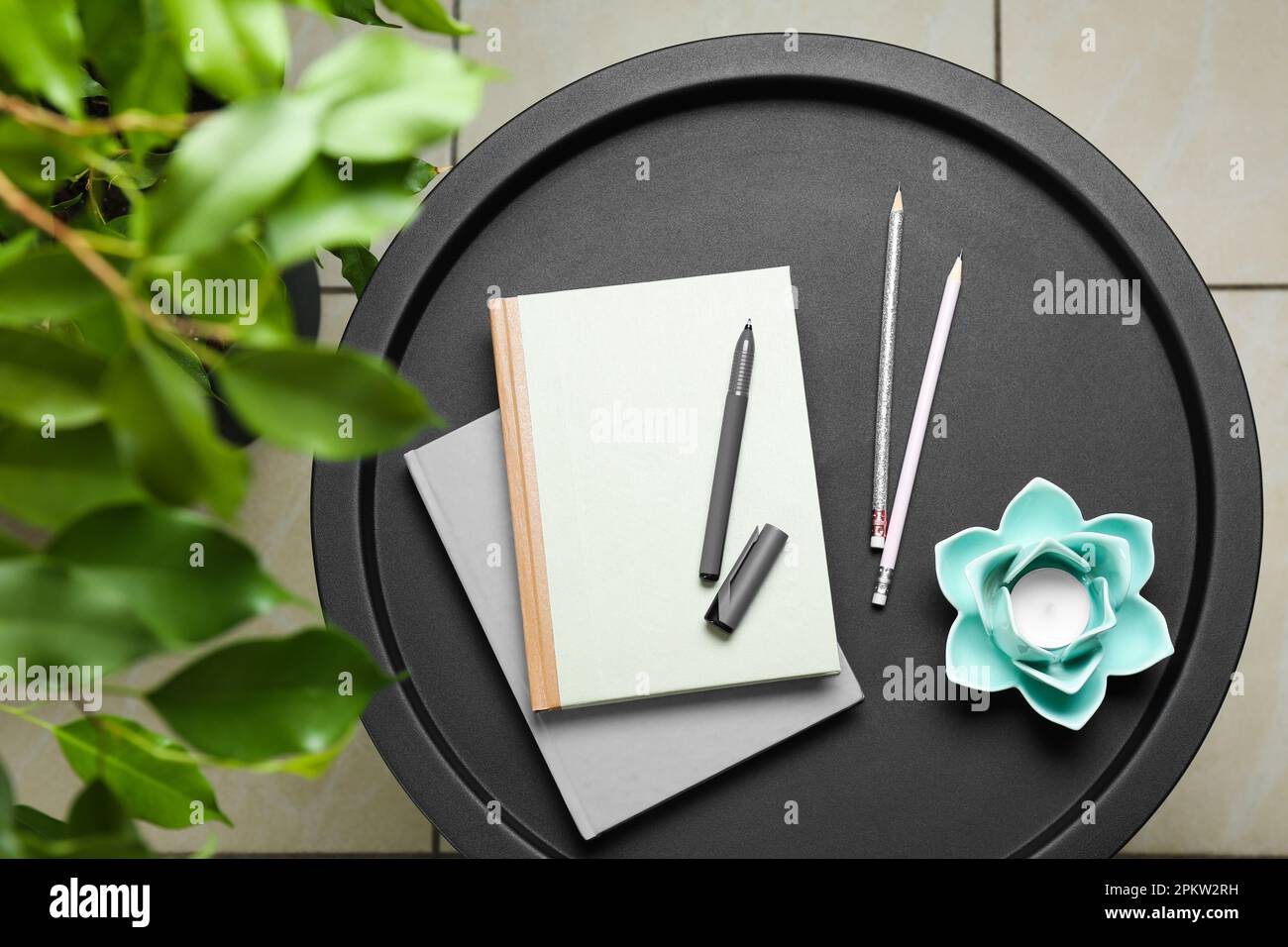 Notebooks, pen, pencils and decor on round table indoors, top view ...