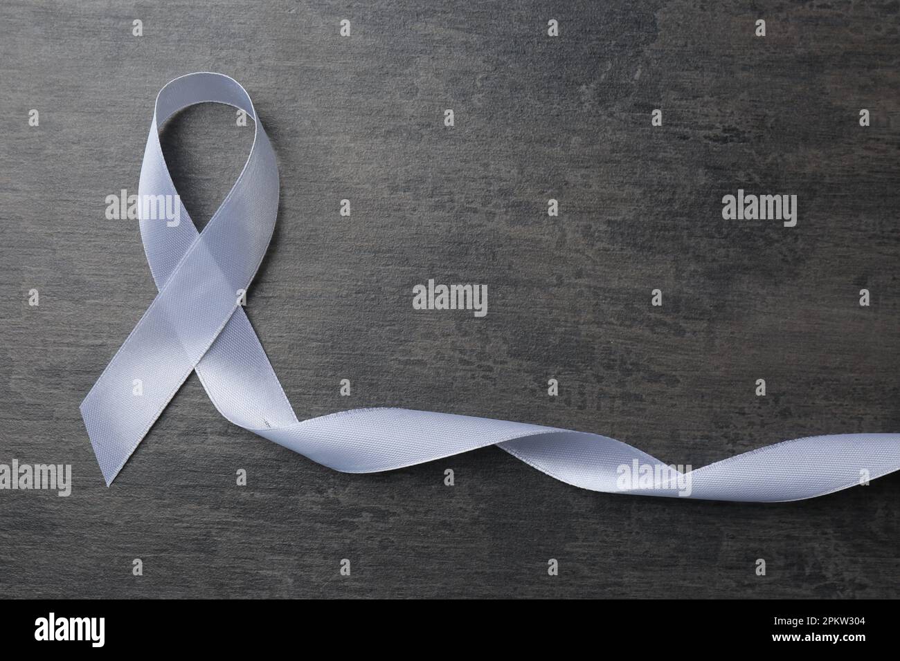 White awareness ribbon on grey table, top view. Space for text Stock ...