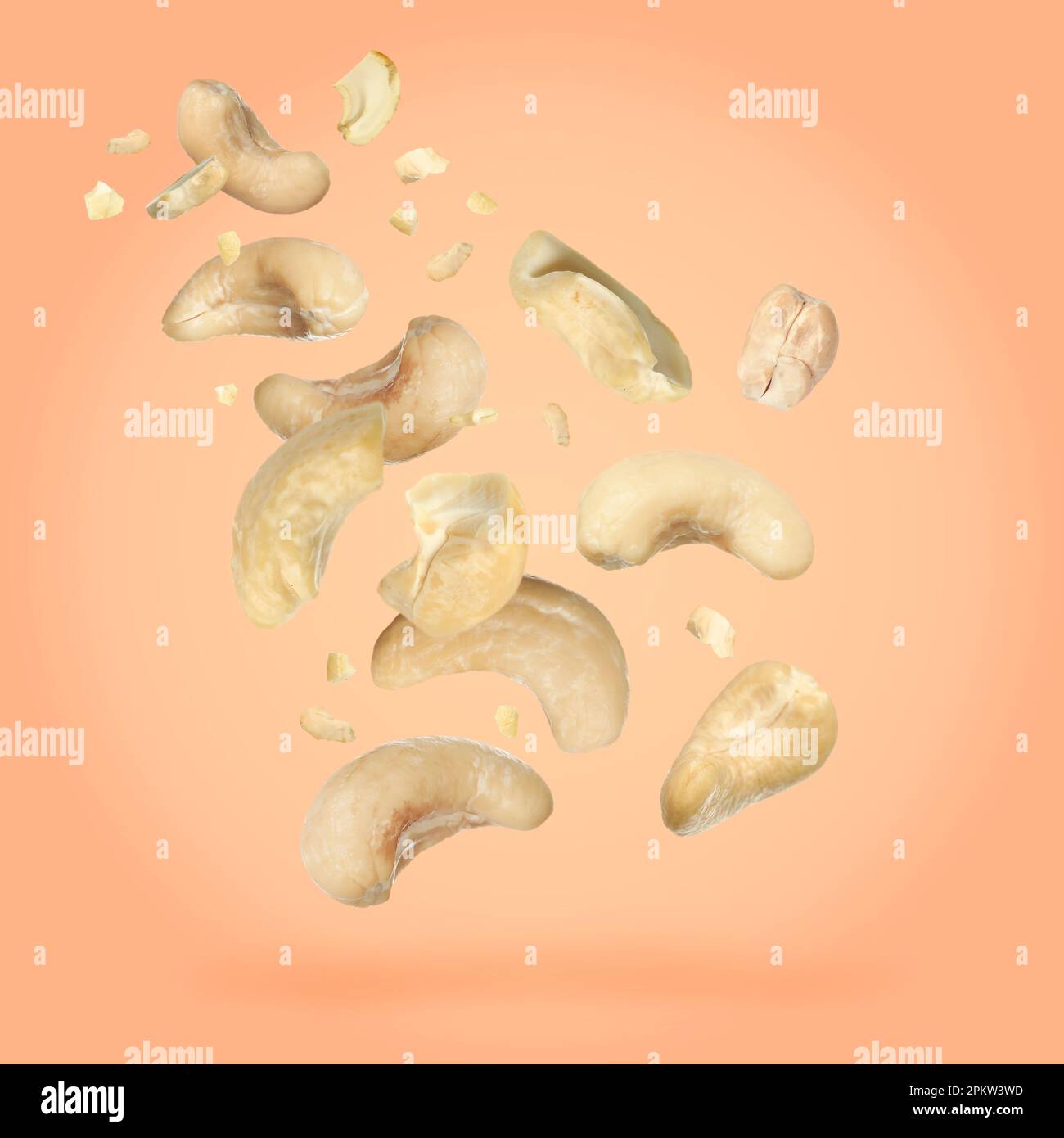Tasty cashew nuts flying on pink background Stock Photo - Alamy