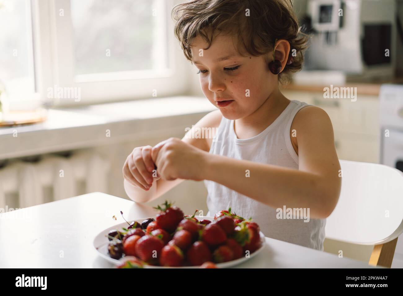 Cute beautiful little boy eating fresh cherry and strawberry Stock ...