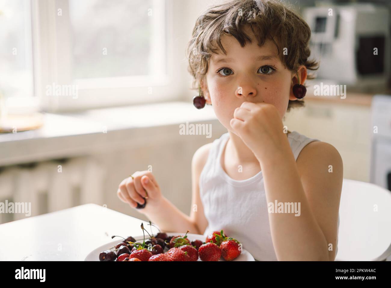 Cute beautiful little boy eating fresh cherry and strawberry Stock ...