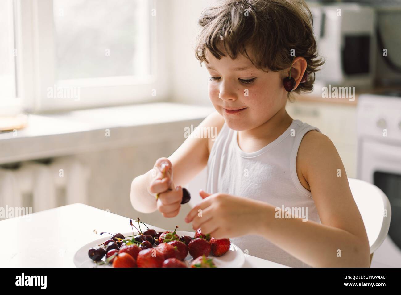Cute beautiful little boy eating fresh cherry and strawberry Stock ...