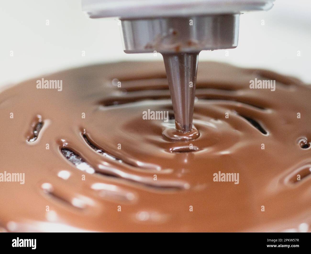 pastry chef preparing a chocolate frosted dripped icing cup cake with ...