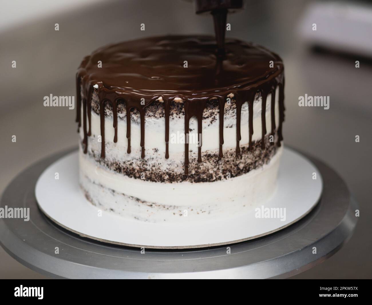 pastry chef preparing a chocolate frosted dripped icing cup cake with ...