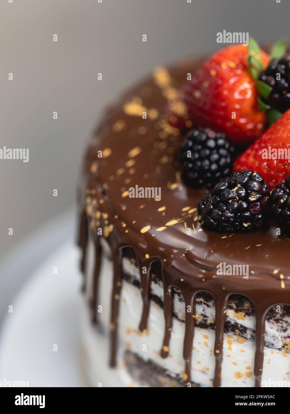 pastry chef preparing a chocolate frosted dripped icing cup cake with ...