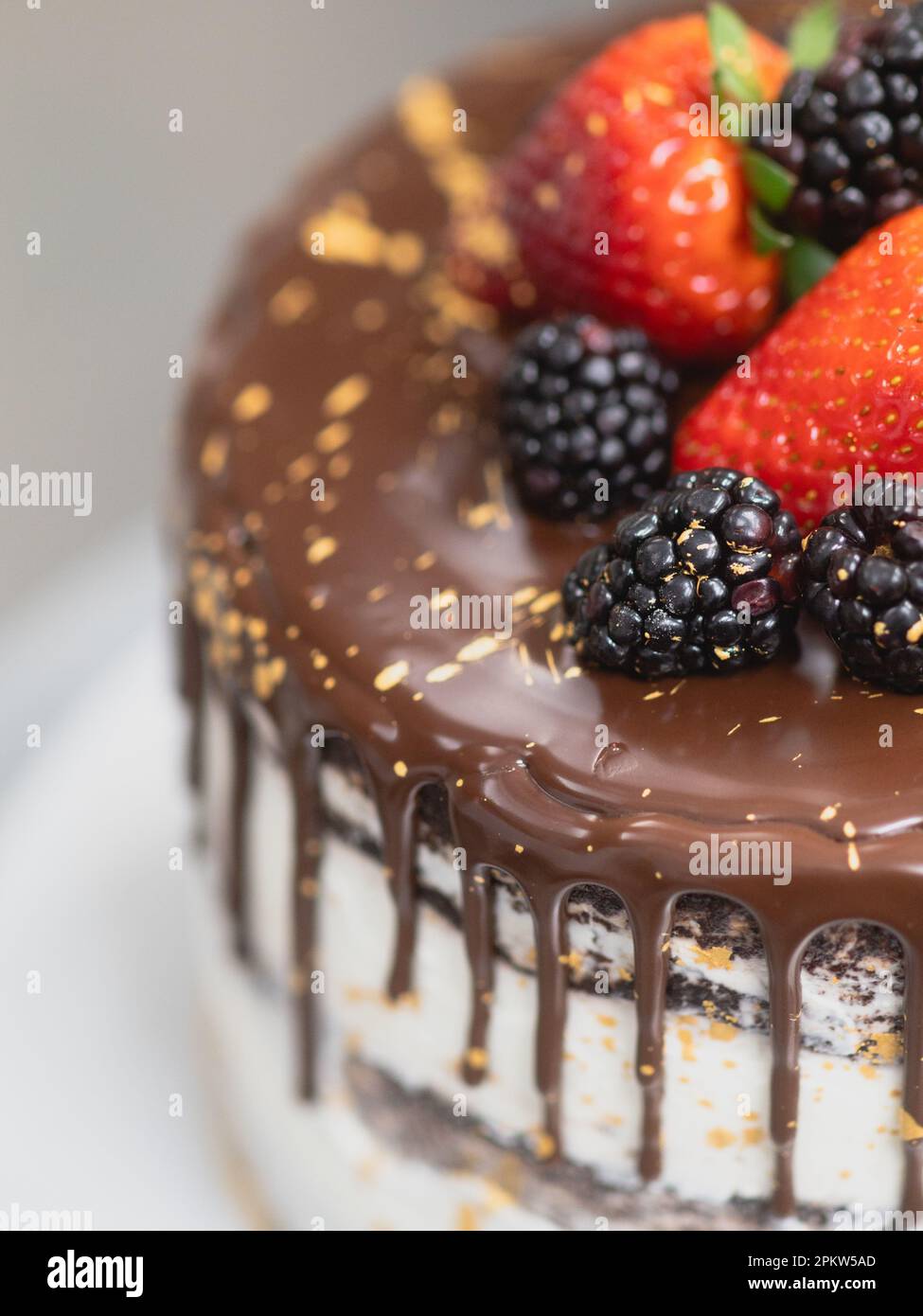 pastry chef preparing a chocolate frosted dripped icing cup cake with ...