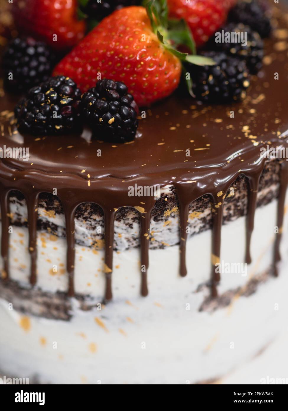 pastry chef preparing a chocolate frosted dripped icing cup cake with ...