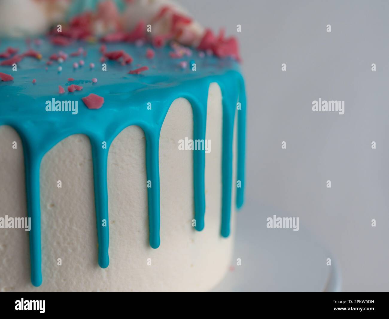 studio shot of chocolate frosted blue dripped icing white cup cake ...