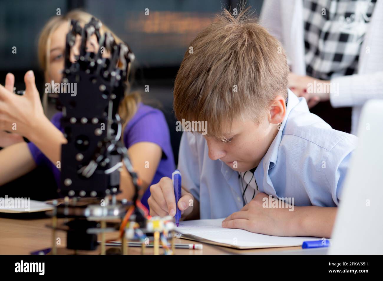 Caucasian two teenager students learning robotic arm in classroom ...