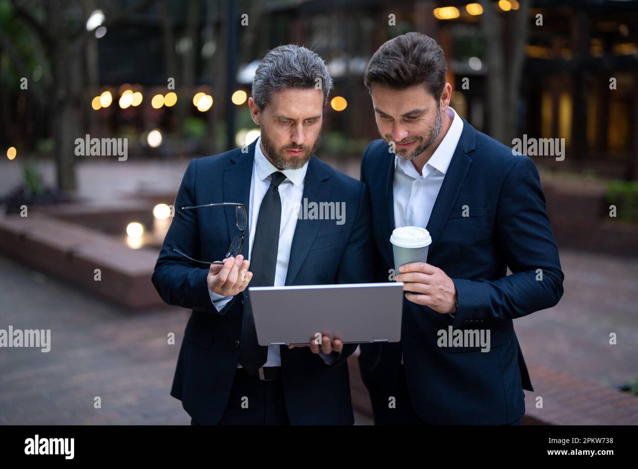 Business men with takeaway coffee and laptop outdoor were strategic in ...