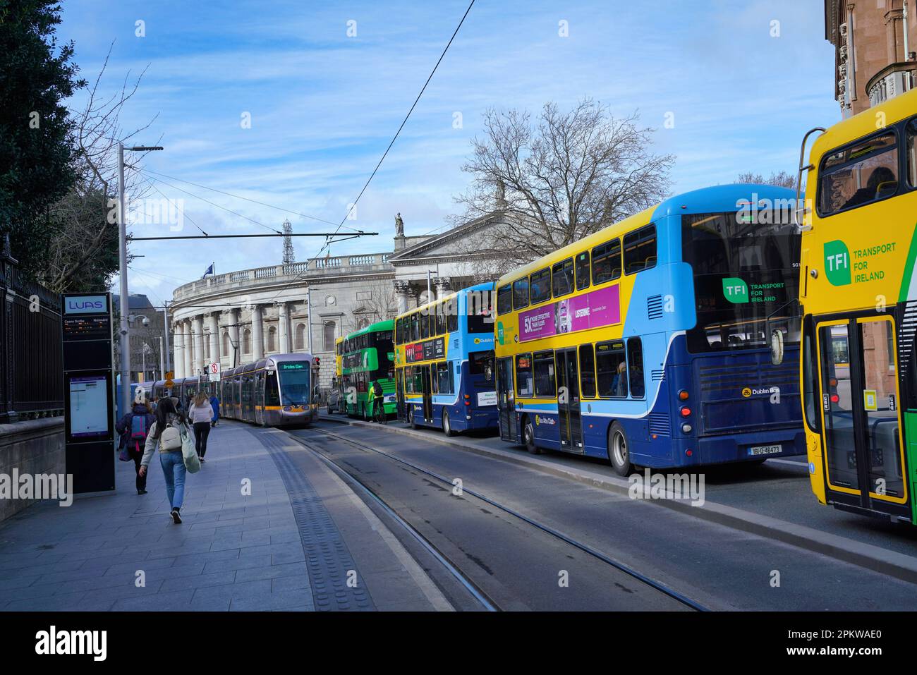 Busy street in Dublin with buses and tram, leading to Parliament Square ...