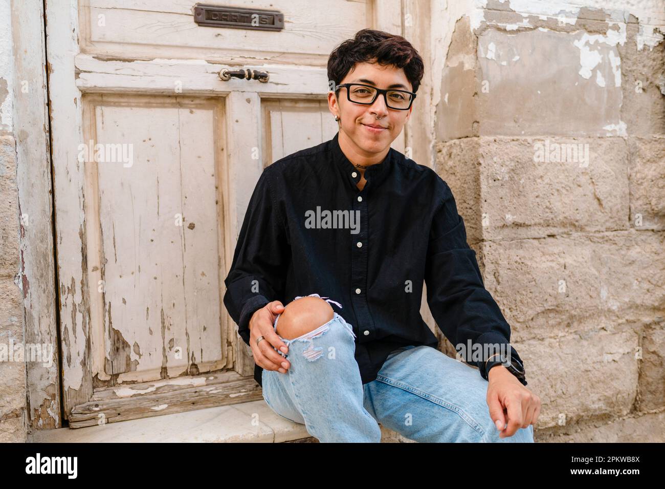 Young transgender man posing sitting on the front steps of a house ...