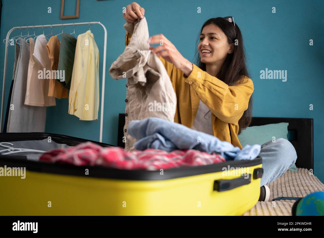 Young woman packing suitcase on bed, closeup. Preparing for summer ...