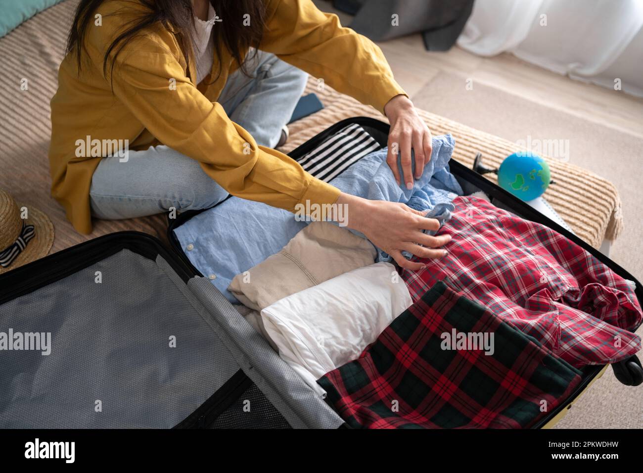 Female hands packing traveler case on bed at home or hotel room ...