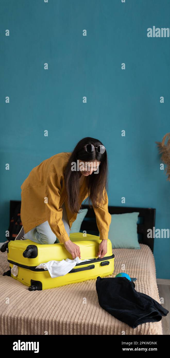 Preparation for vacation. Happy woman packing and trying to close ...
