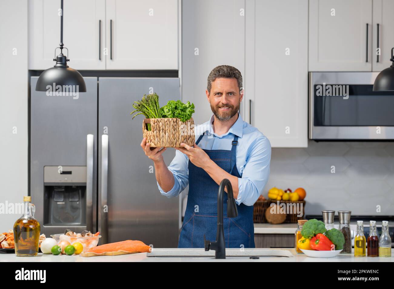 Portrait of happy smiling man in cook apron preparing fresh natural ...