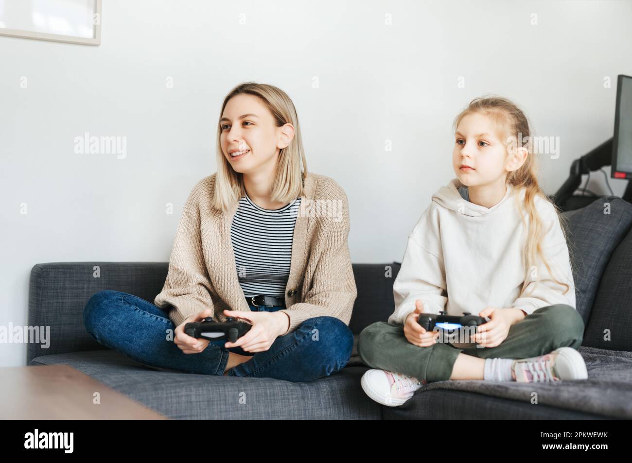 Young women and little girl joyful playing video games with controller ...