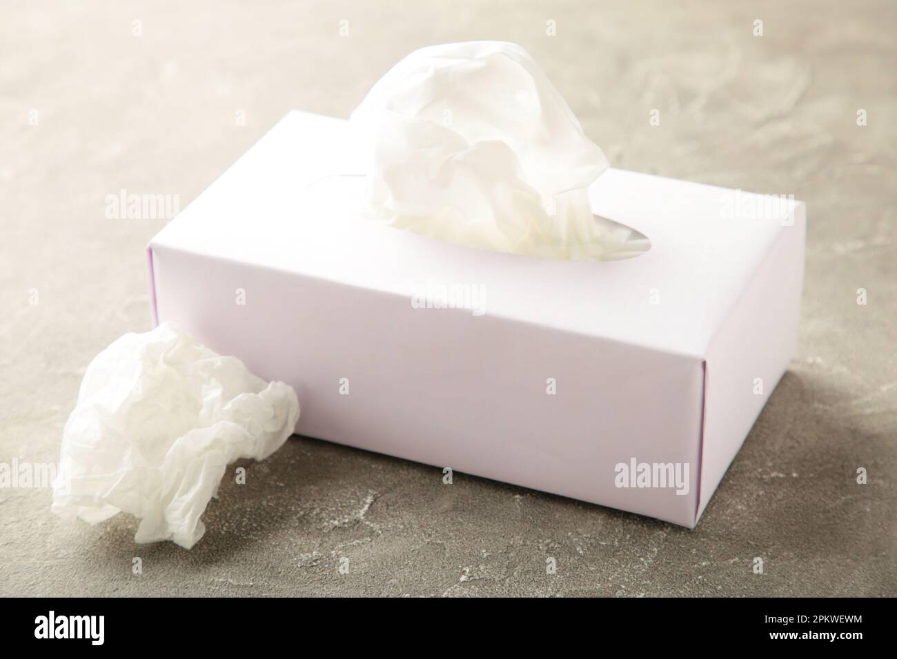 Box with paper tissues and used crumpled napkins on grey background ...