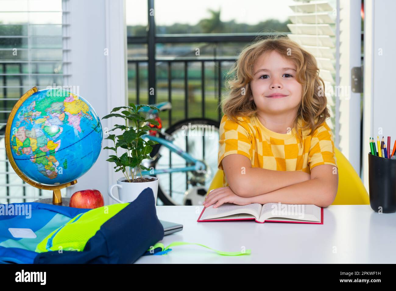 Little student school child doing homework at home. Child reading book ...