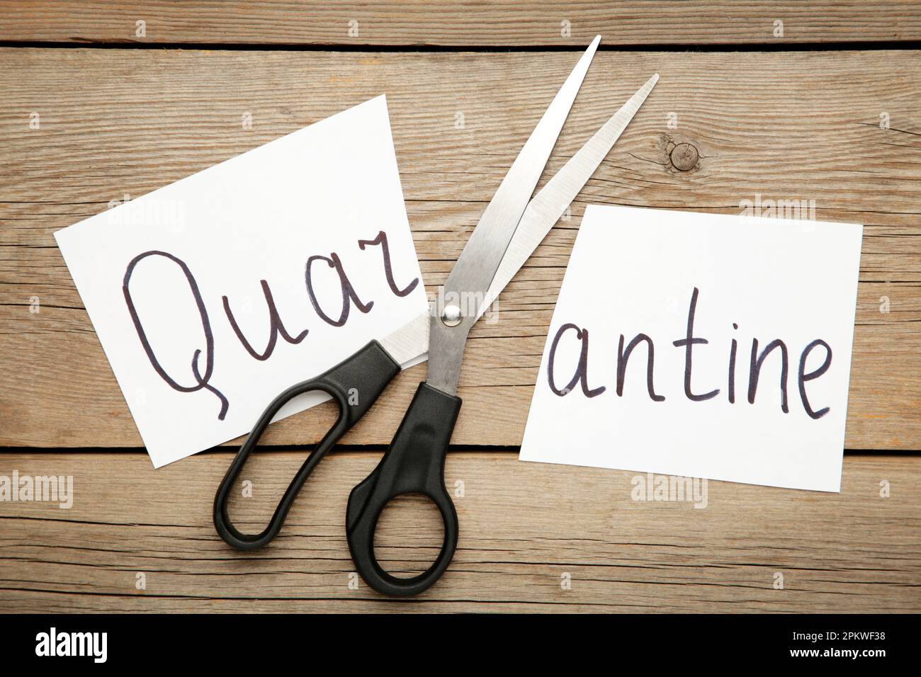 Scissors cutting a piece of paper with QUARANTINE word Stock Photo - Alamy