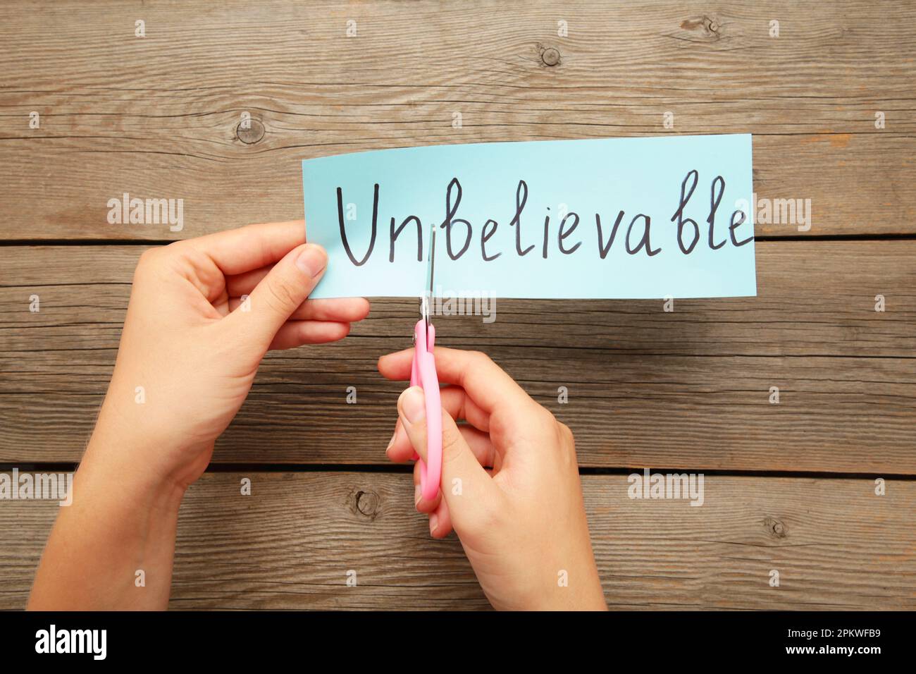 Scissors cutting white paper with the text unbelivable, change word to ...