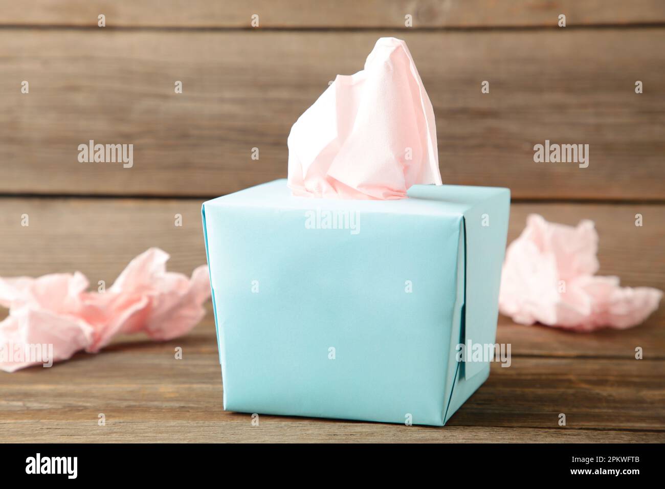 Blue box with paper tissues and used crumpled napkins on grey wooden ...