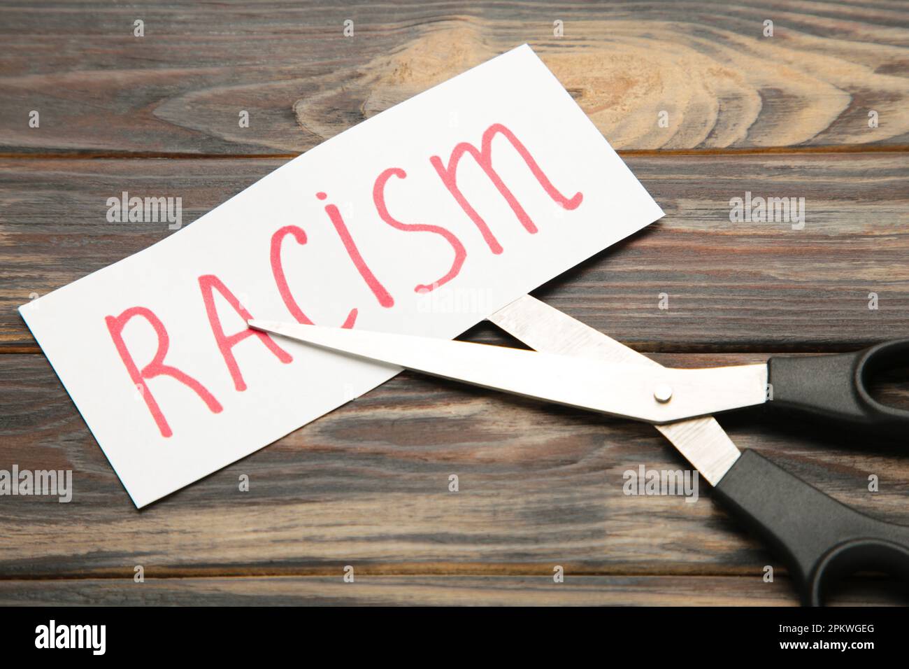 Top view of black scissors and cutted paper card with word Racism on ...