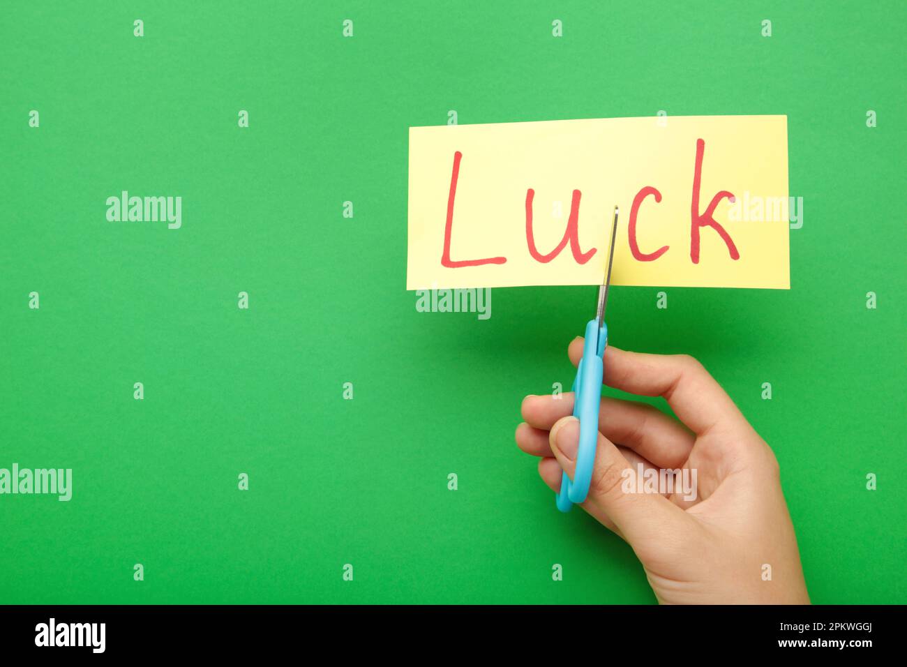 Cut paper with word LUCK and scissors on green background, closeup. Top ...