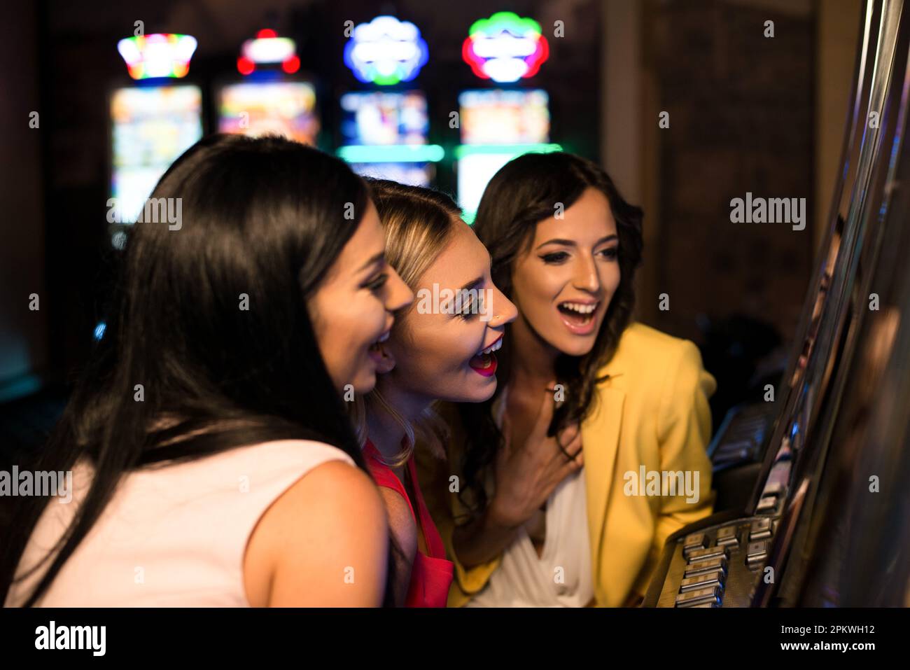 Young Women at Night at the Automat Machine in a Casino and Celebrate ...